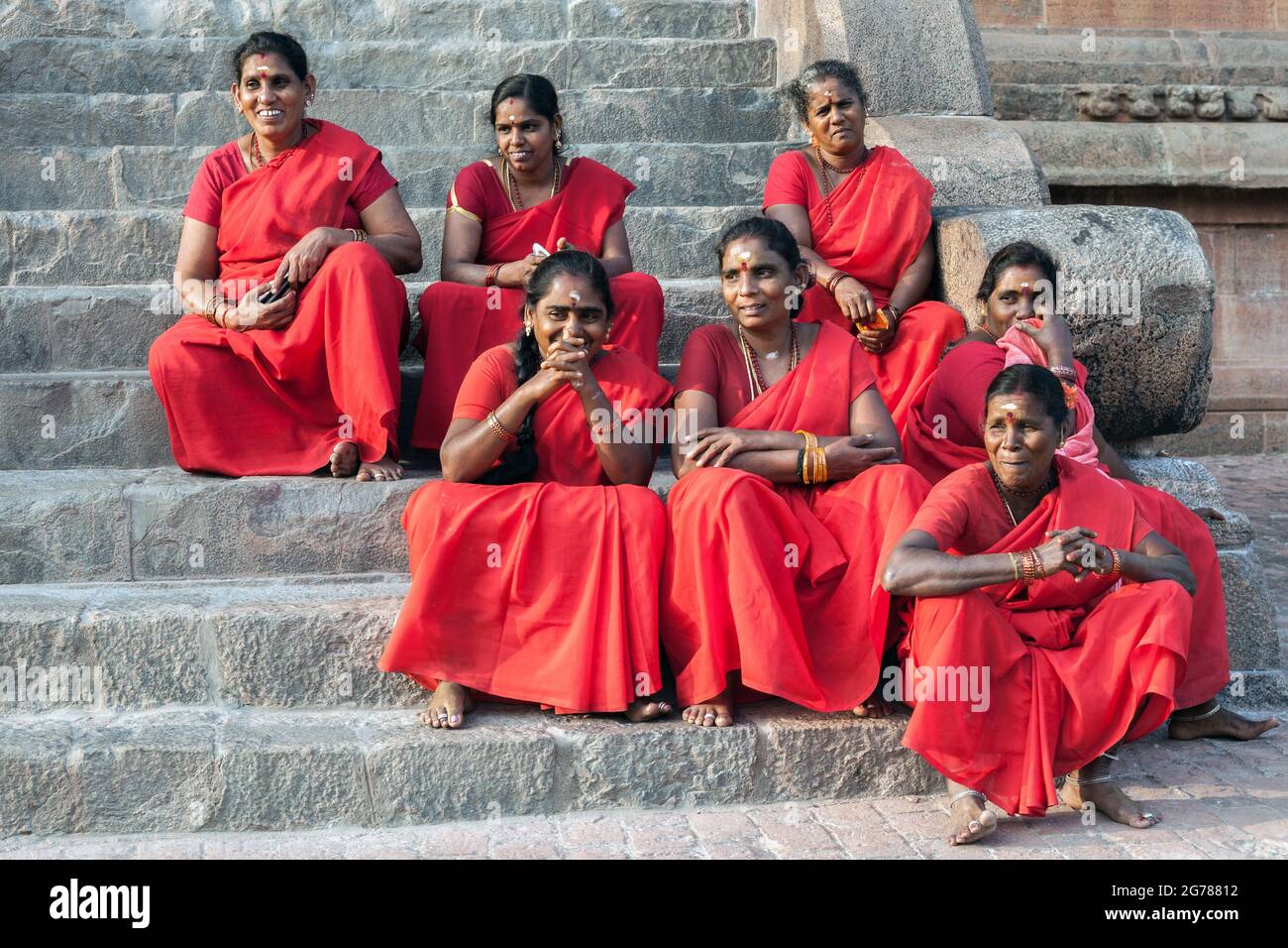 Group of Indian hindu devotees in red saris seated on steps posing for ...