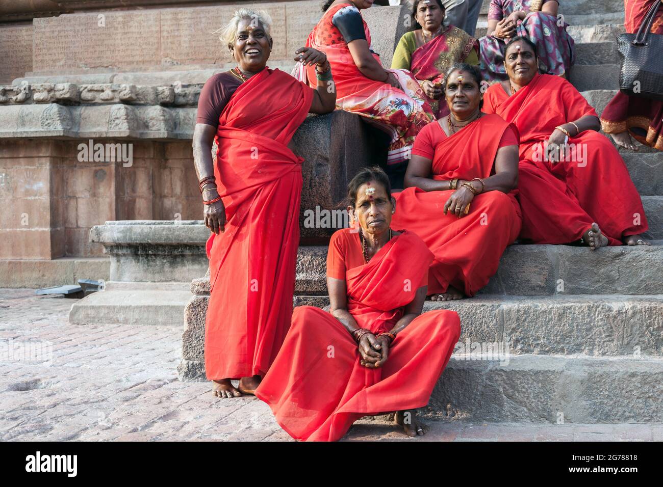 Group of Indian hindu devotees in red saris seated on steps posing for ...
