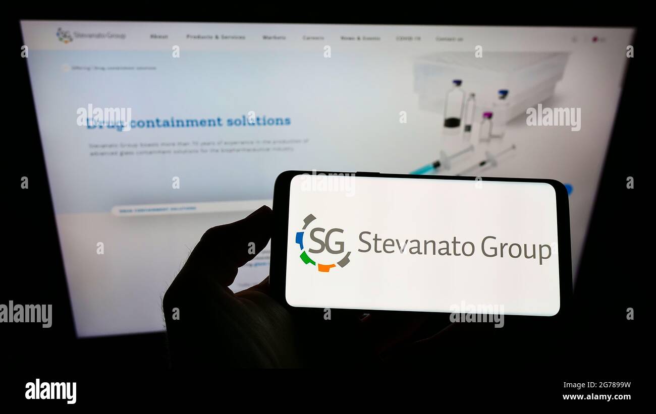 Person holding smartphone with logo of Italian glass company Stevanato ...