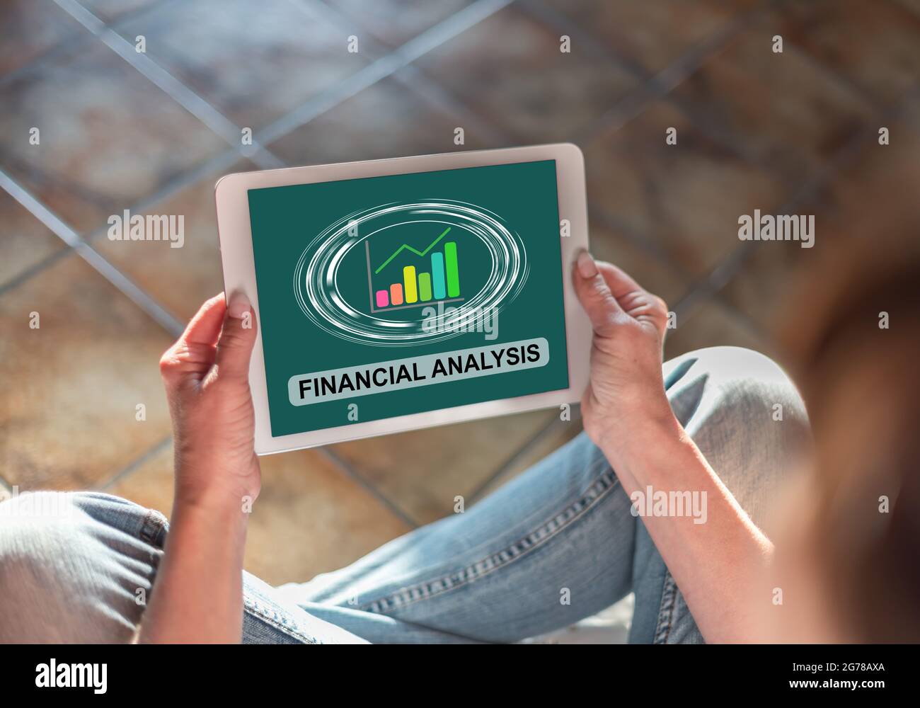Woman sitting on the floor with a tablet showing financial analysis ...