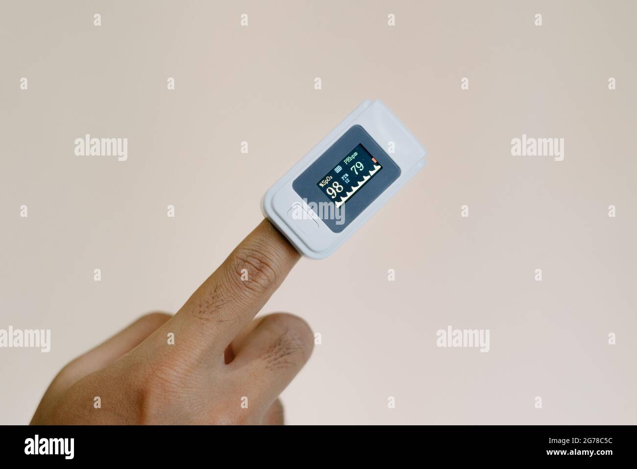 An index finger clamped with oximeter shows the oxygen saturation level ...