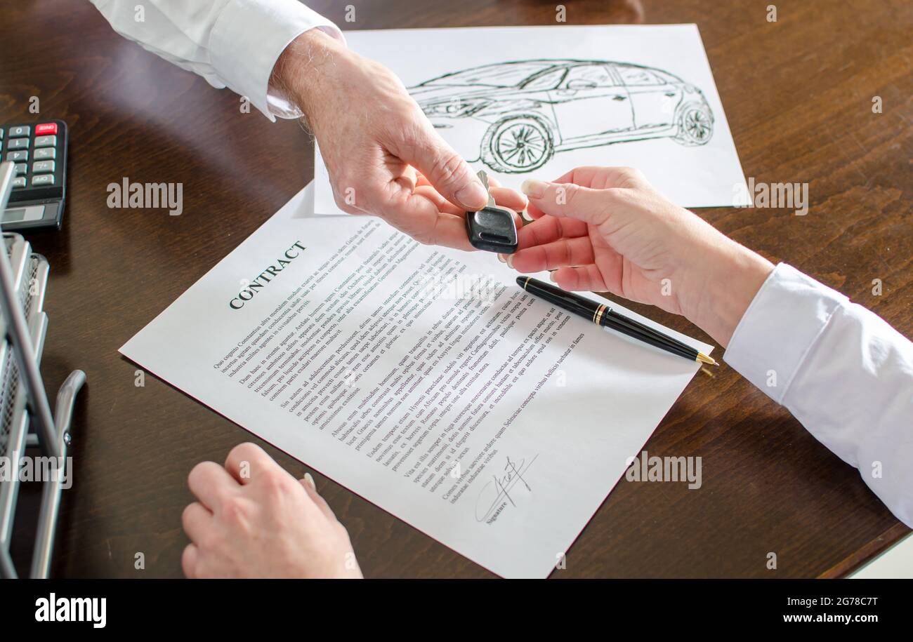 Dealer giving car key to customer after contract signature Stock Photo ...
