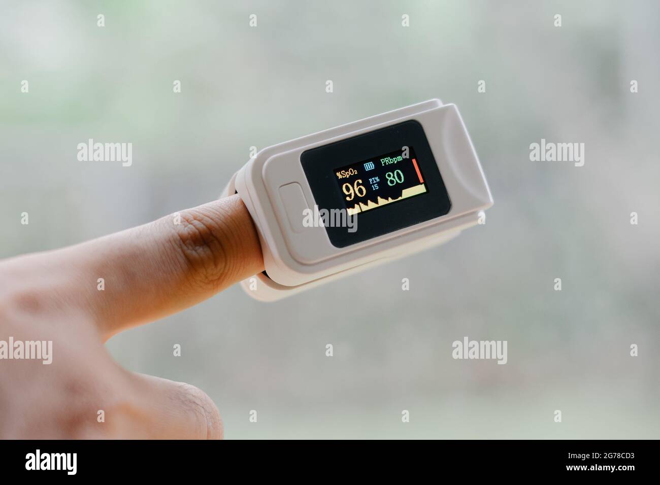An index finger clamped with oximeter shows the oxygen saturation level ...