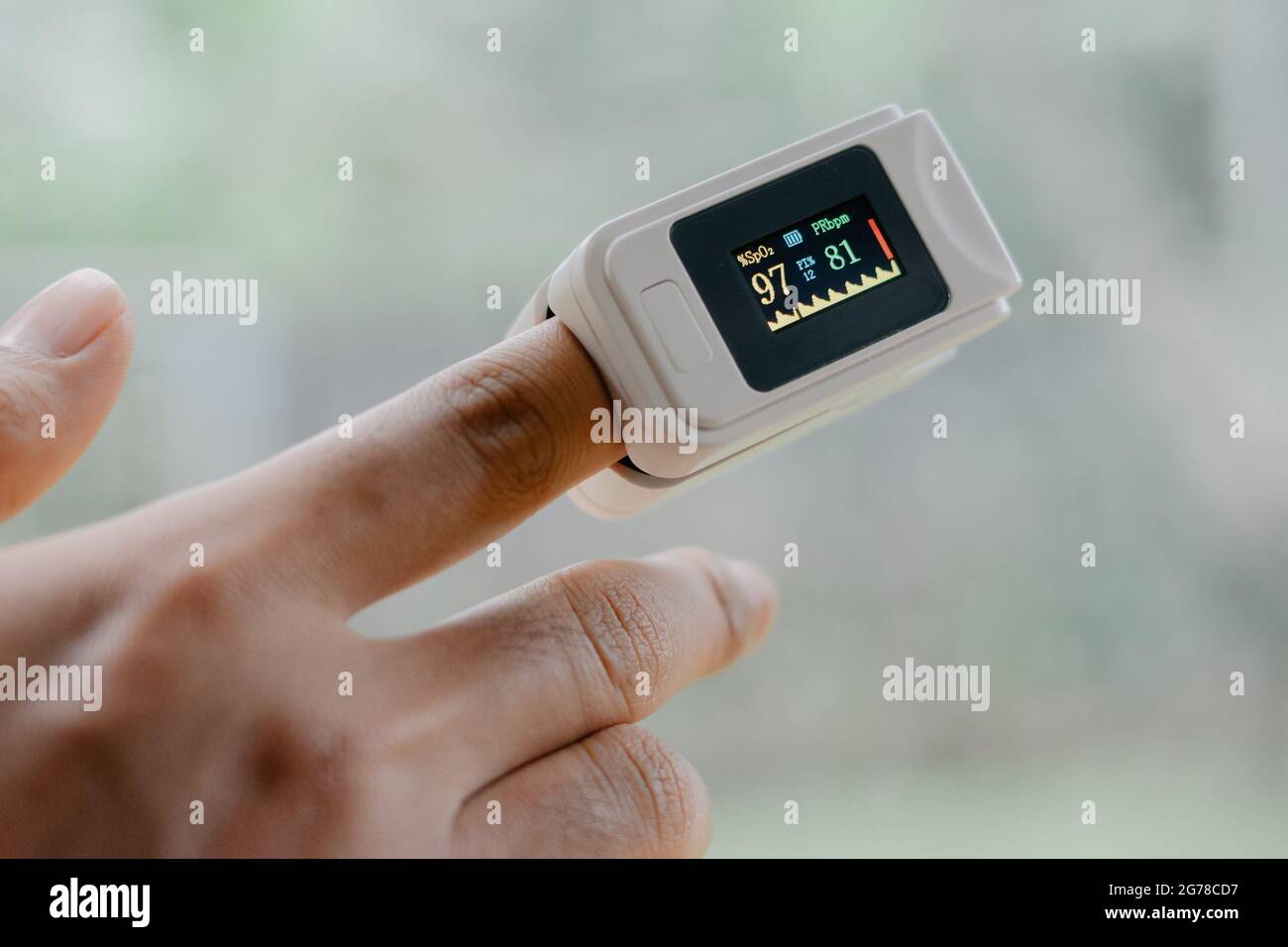 An index finger clamped with oximeter shows the oxygen saturation level ...