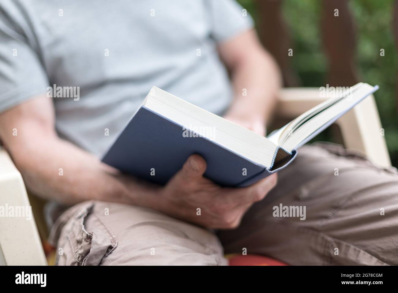 Man sitting outdoor reading a book Stock Photo - Alamy