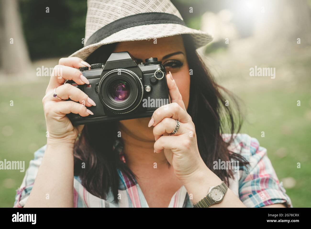Portrait of beautiful young woman taking pictures in a park, light ...