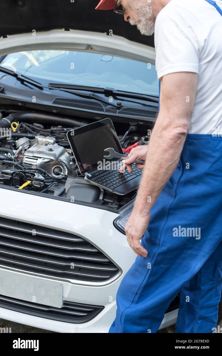Car mechanic using laptop for checking car engine Stock Photo - Alamy