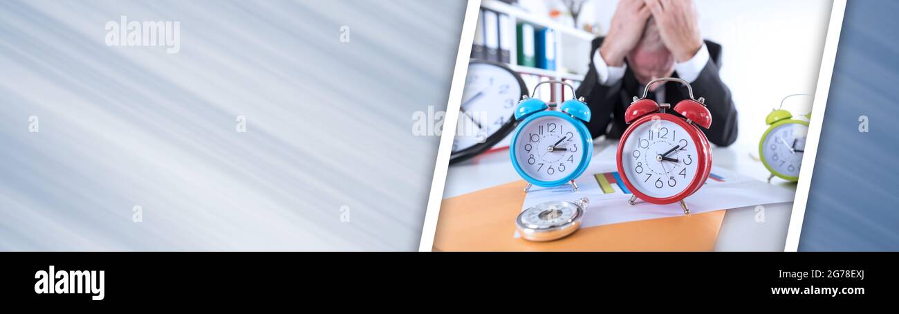 Stressed businessman behind his desk full of alarm clocks. panoramic banner Stock Photo - Alamy