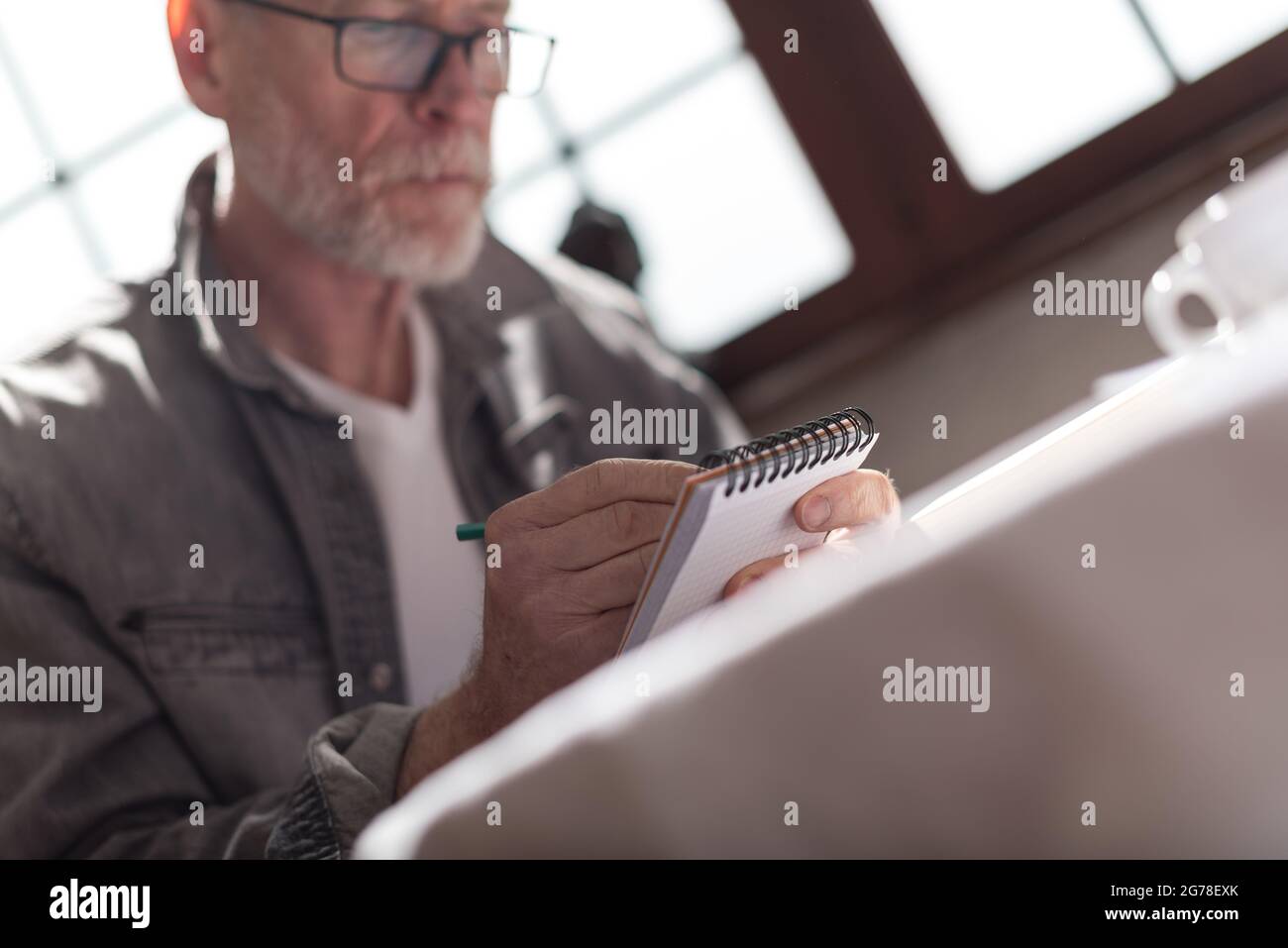 Senior man taking notes at home, hard light effect Stock Photo - Alamy