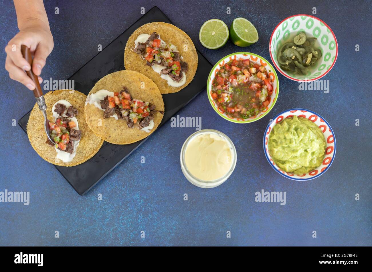 hand preparing tacos in a table full of ingredients Stock Photo - Alamy