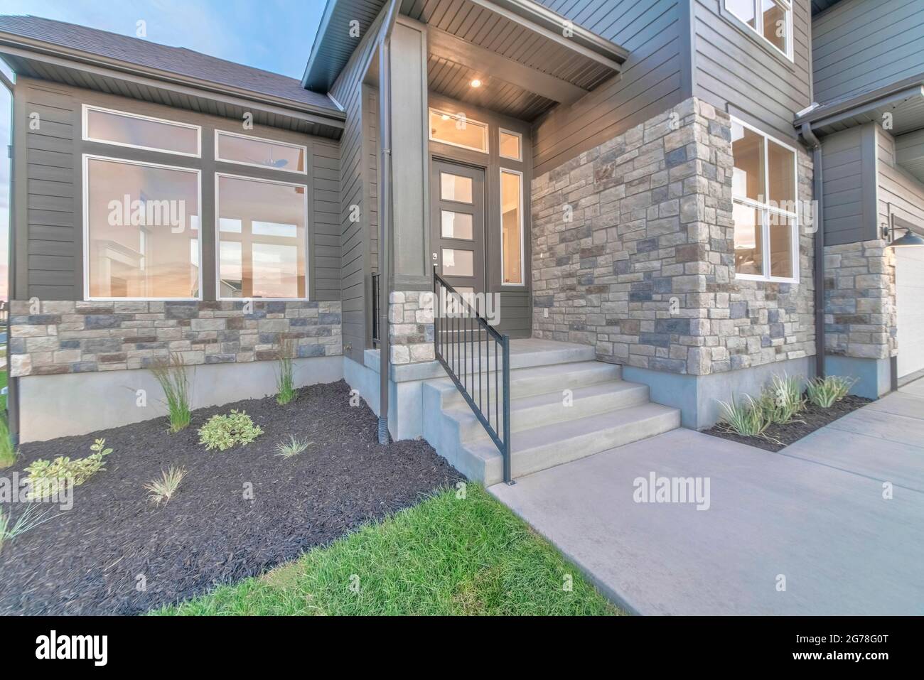 Two storey home facade with stone brick wall and glass paned gray front ...