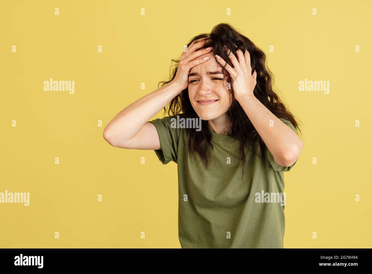 Sad, confused young Caucasian woman posing isolated over yellow studio ...