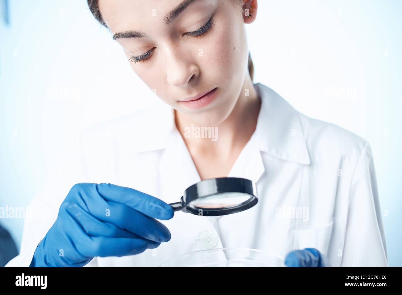 female laboratory assistant in a white coat looking through a ...