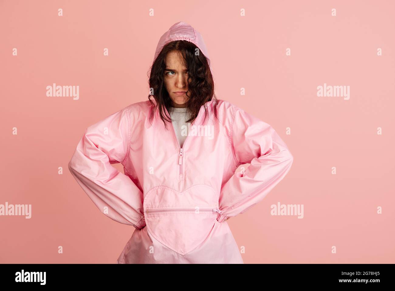 Studio image of one young Caucasian woman standing posing on light pink ...