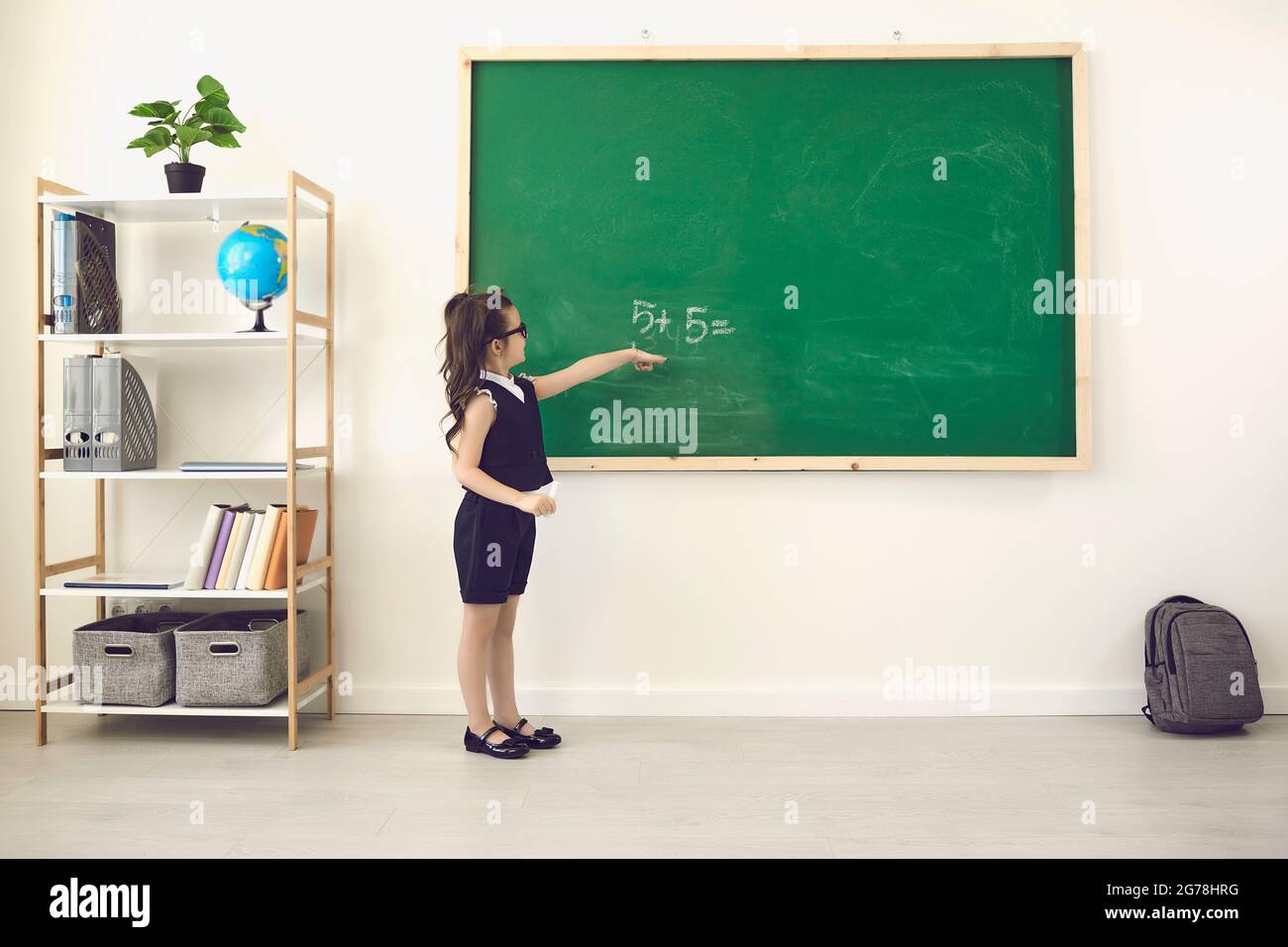 Back to school. Rear view of a schoolgirl in chalk writes on a school ...