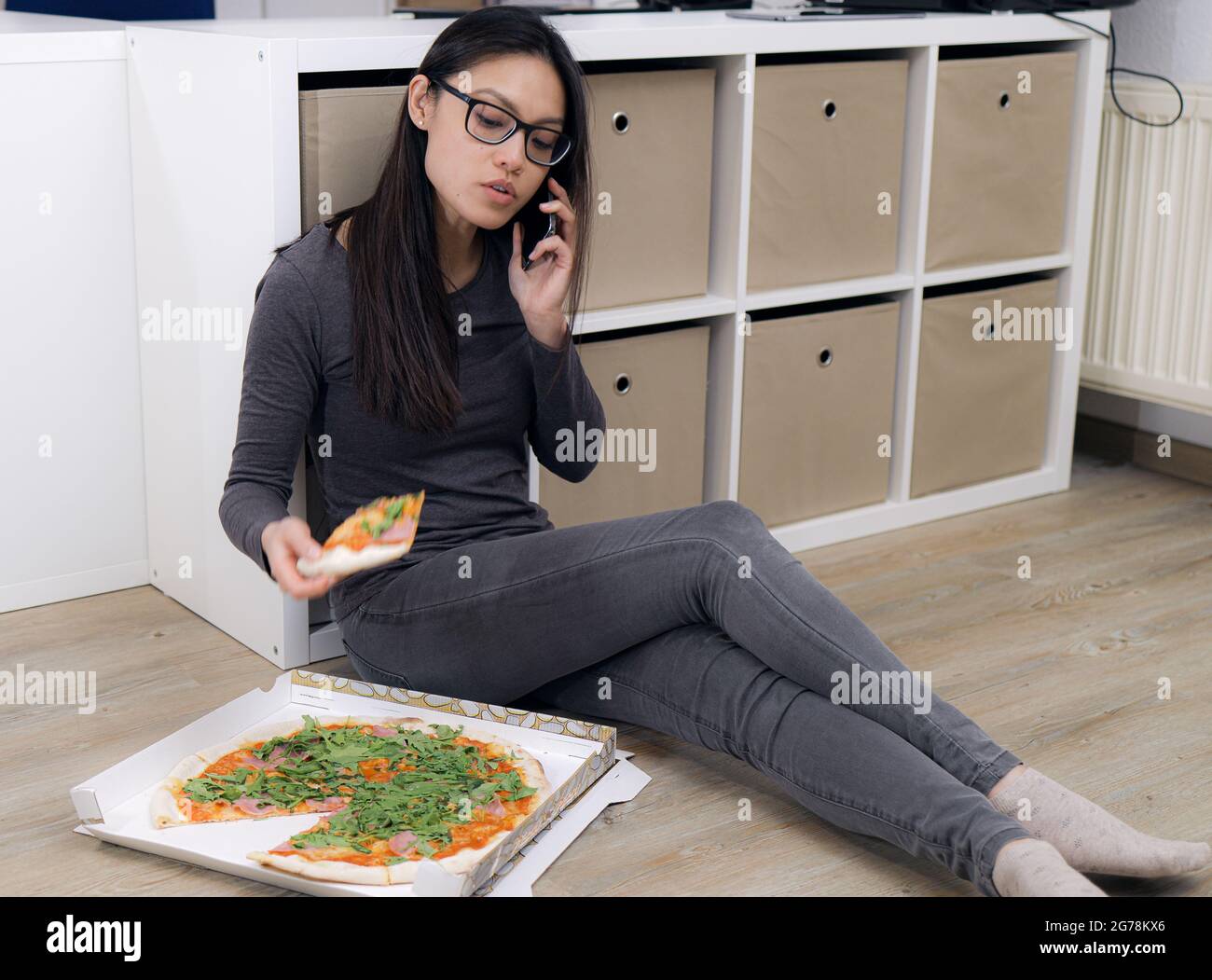 Young woman takes a phone call while eating pizza Stock Photo - Alamy