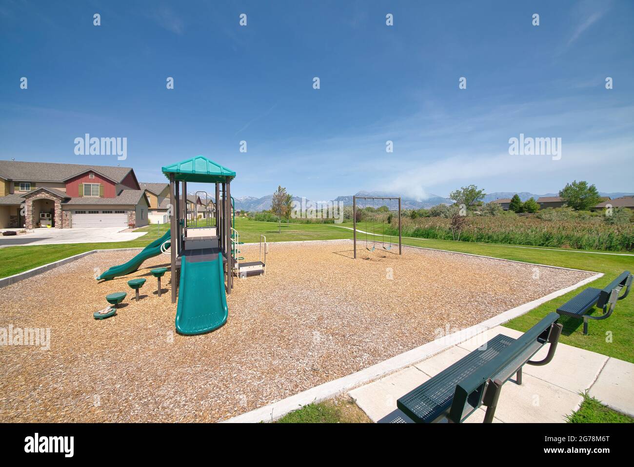 Children swings and slides at a community playground with mountain and ...