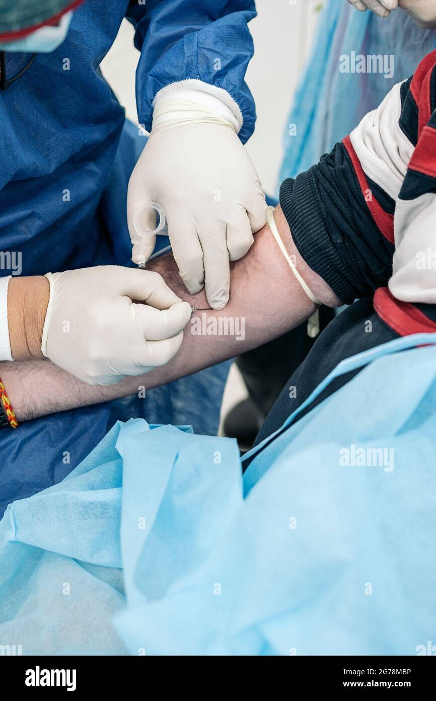 Unrecognized doctor draws blood from a patient in medical clinic Stock ...