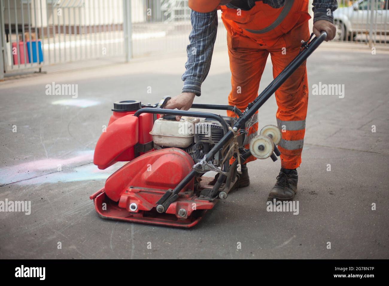 Asphalt laying. Leveling the road. A worker compresses warm asphalt ...