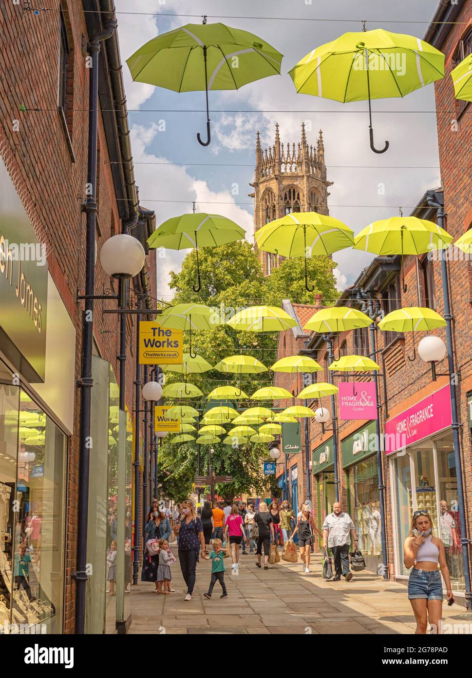 A pedestrianised street with an overhead display of yellow umbrellas ...