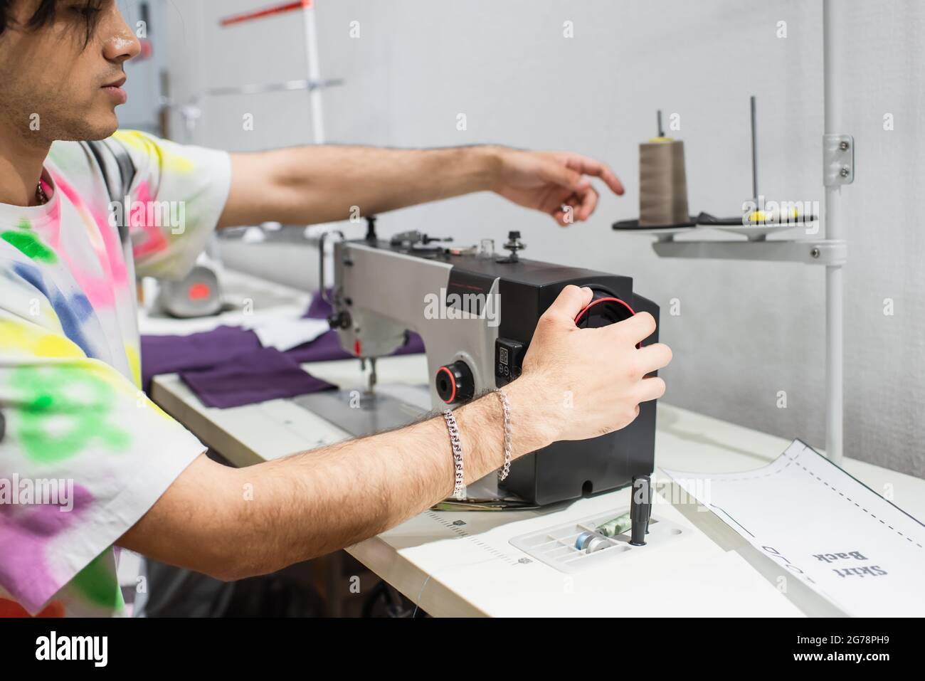 cropped view of young tailor regulating sewing machine in fashion ...