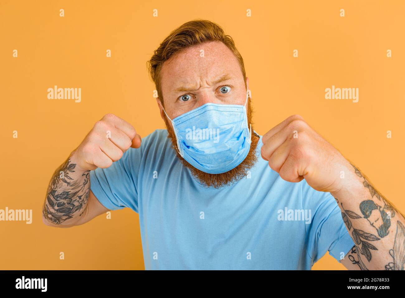 Angry man with beard, tattoo and mask for covid-19 wants to fight Stock ...