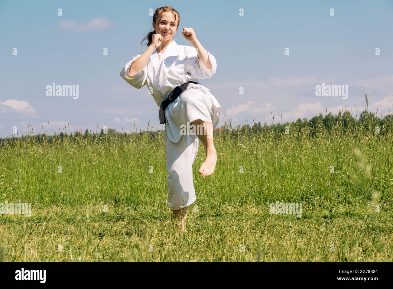 teenage girl practicing karate kata outdoors, prepares to yoko geri ...