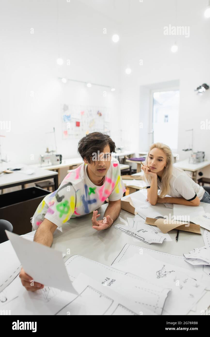 stylish designer showing paper to colleague near sewing patterns Stock ...