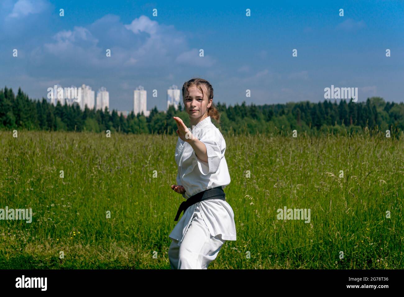 teenage girl practicing karate kata outdoors, performs soto uke or ...