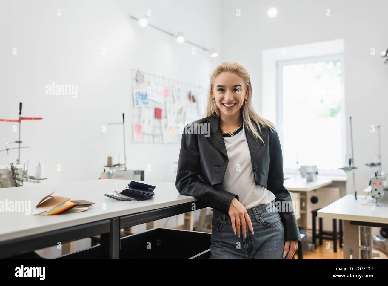 cheerful fashion designer looking at camera near color swatches in ...