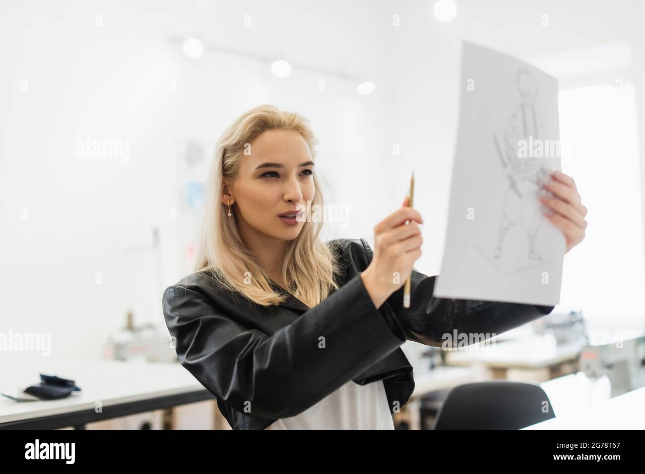 young fashion designer measuring proportions of drawing with pencil ...