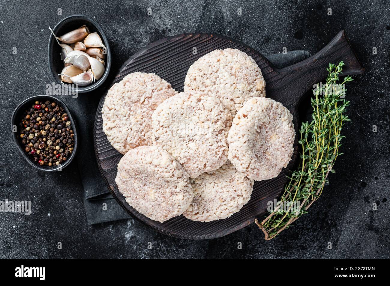 Uncooked Raw breaded patty cutlets on wooden chopping board with herbs ...