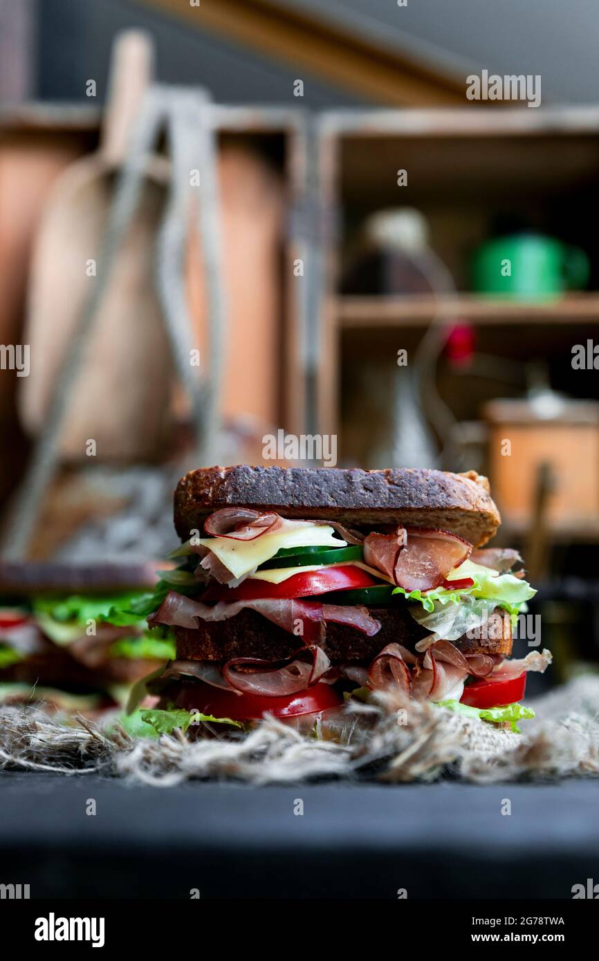 Big sandwich with bread, prosciutto, lettuce, tomtatoes, cucumber and ...