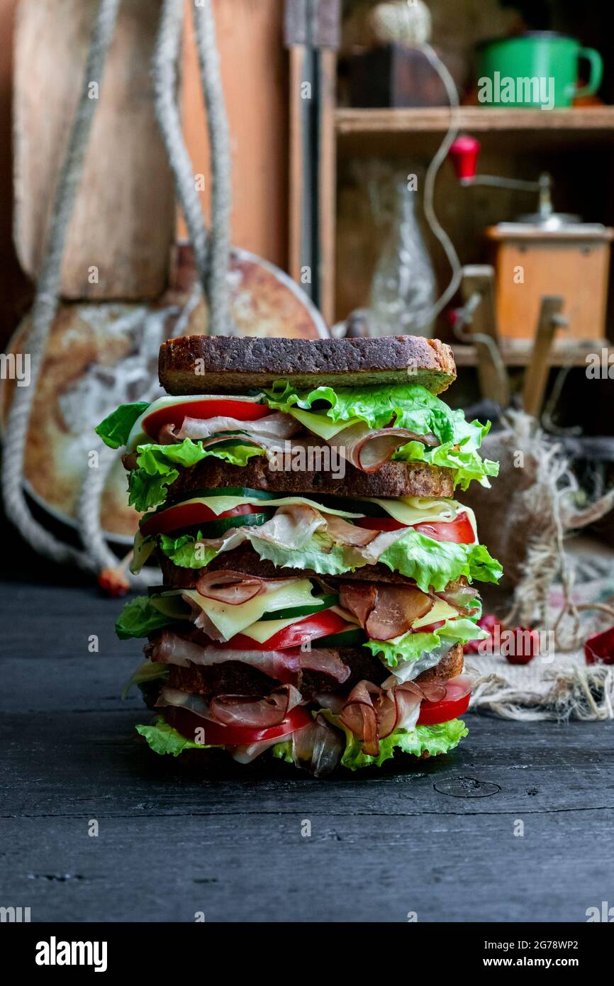 Big sandwich with bread, prosciutto, lettuce, tomtatoes, cucumber and ...