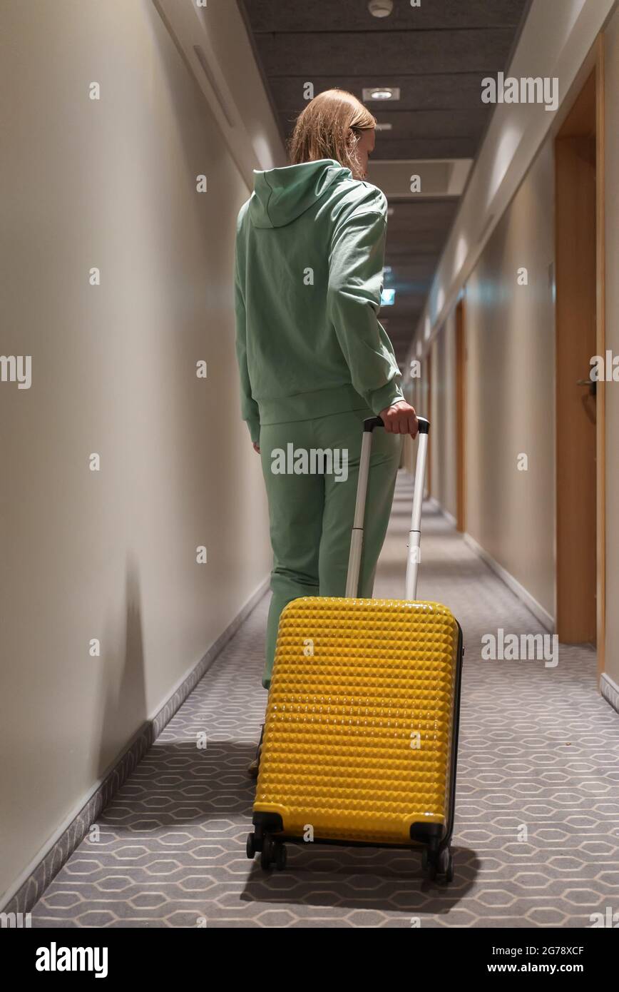 Woman with suitcase in the hallway at the hotel. Check in at the hotel ...
