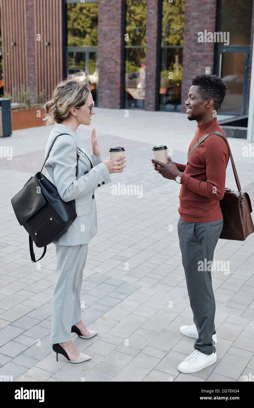 Two successful multiracial colleagues talking against building exterior ...