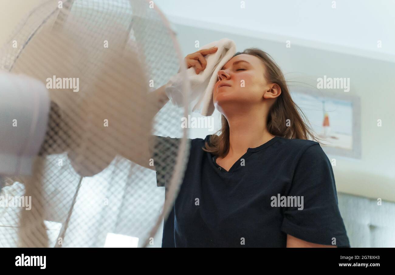 Woman tries to cool off during the intense heat in front of cooling fan ...