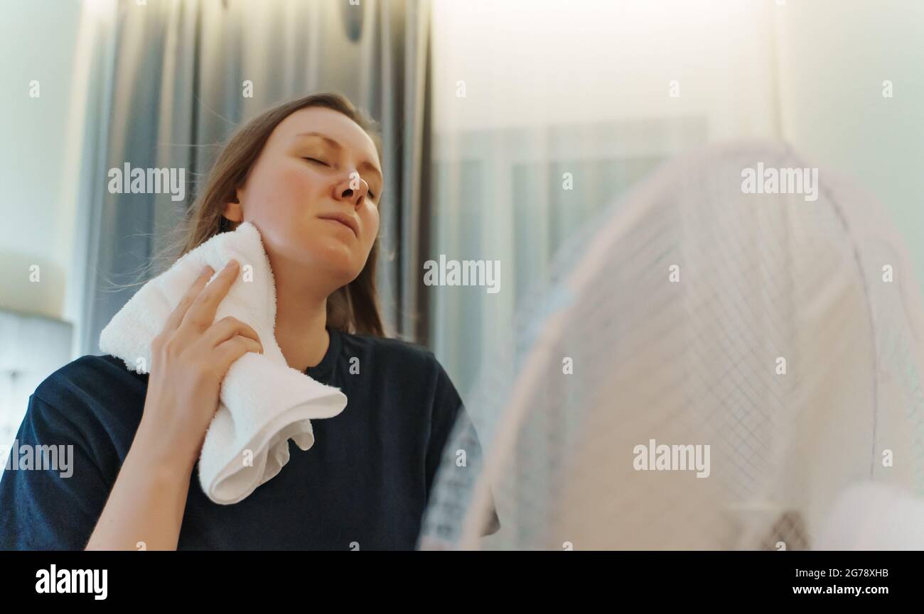 Woman tries to cool off during the intense heat in front of cooling fan ...