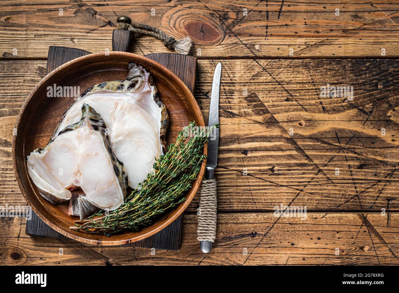 Raw wolffish or wolf fish fillet in a wooden plate. wooden background ...