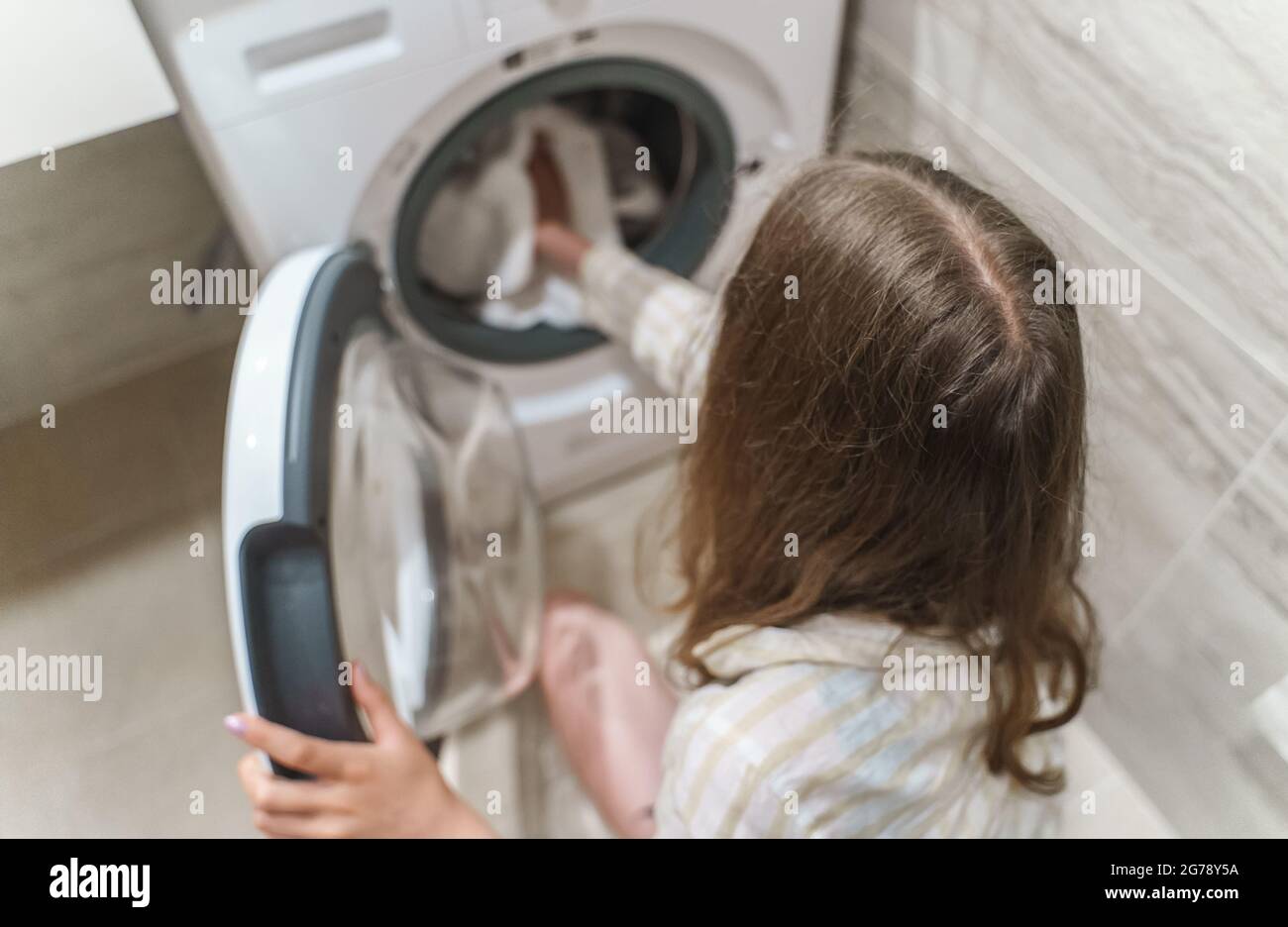 Teenage girl loading clothes into washing machine Stock Photo - Alamy