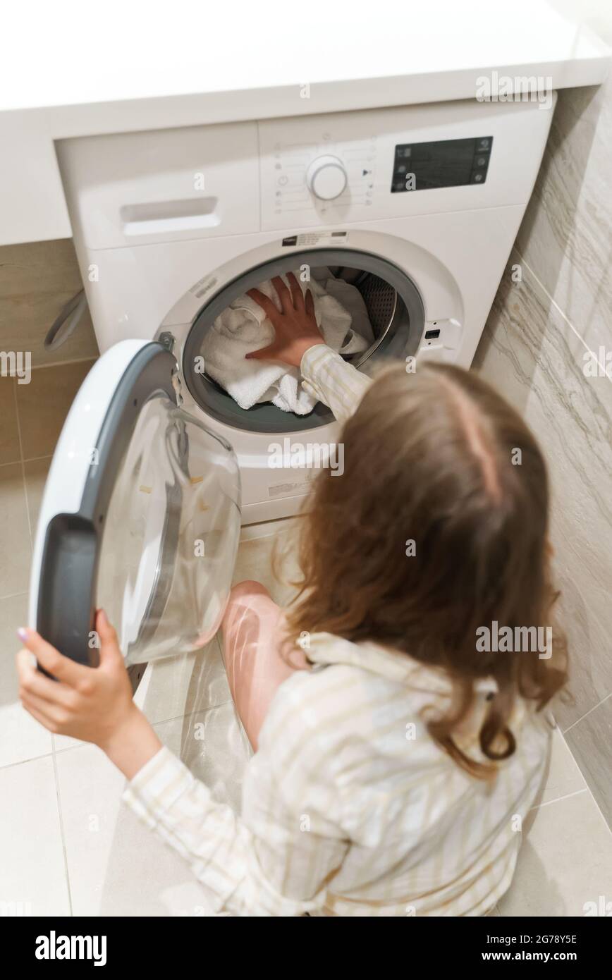 Teenage girl loading clothes into washing machine Stock Photo - Alamy