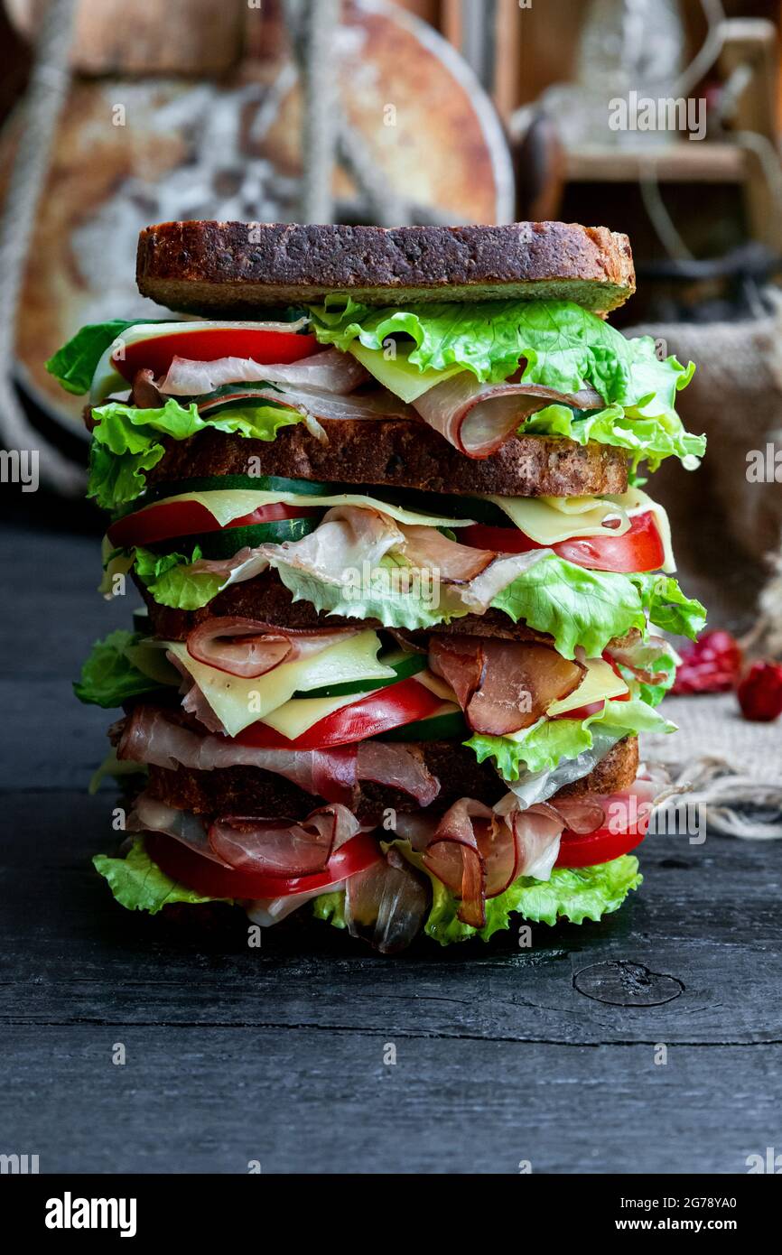 Big sandwich with bread, prosciutto, lettuce, tomtatoes, cucumber and ...