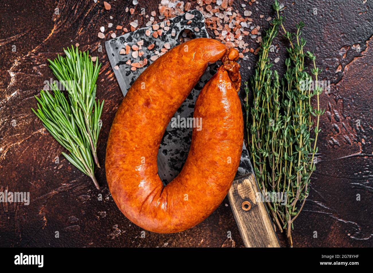Hot Smoked sausage on a butcher rustic cleaver with herbs. Dark ...