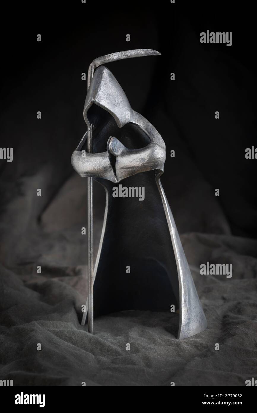 A praying metal monk figure with a scythe Stock Photo - Alamy