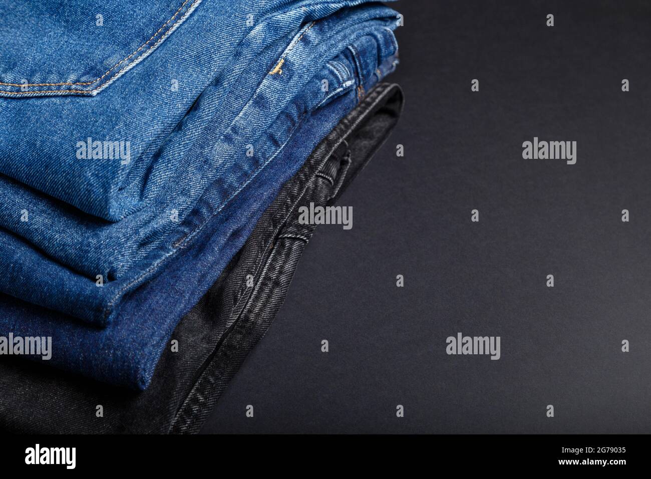 Stack of blue jeans on black background with copy space. Frame made of ...