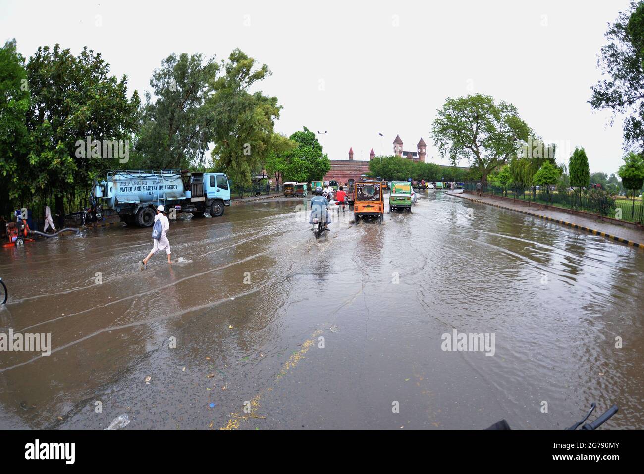 Lahore, Pakistan. 12th July, 2021. Pakistani commuters wade through a ...