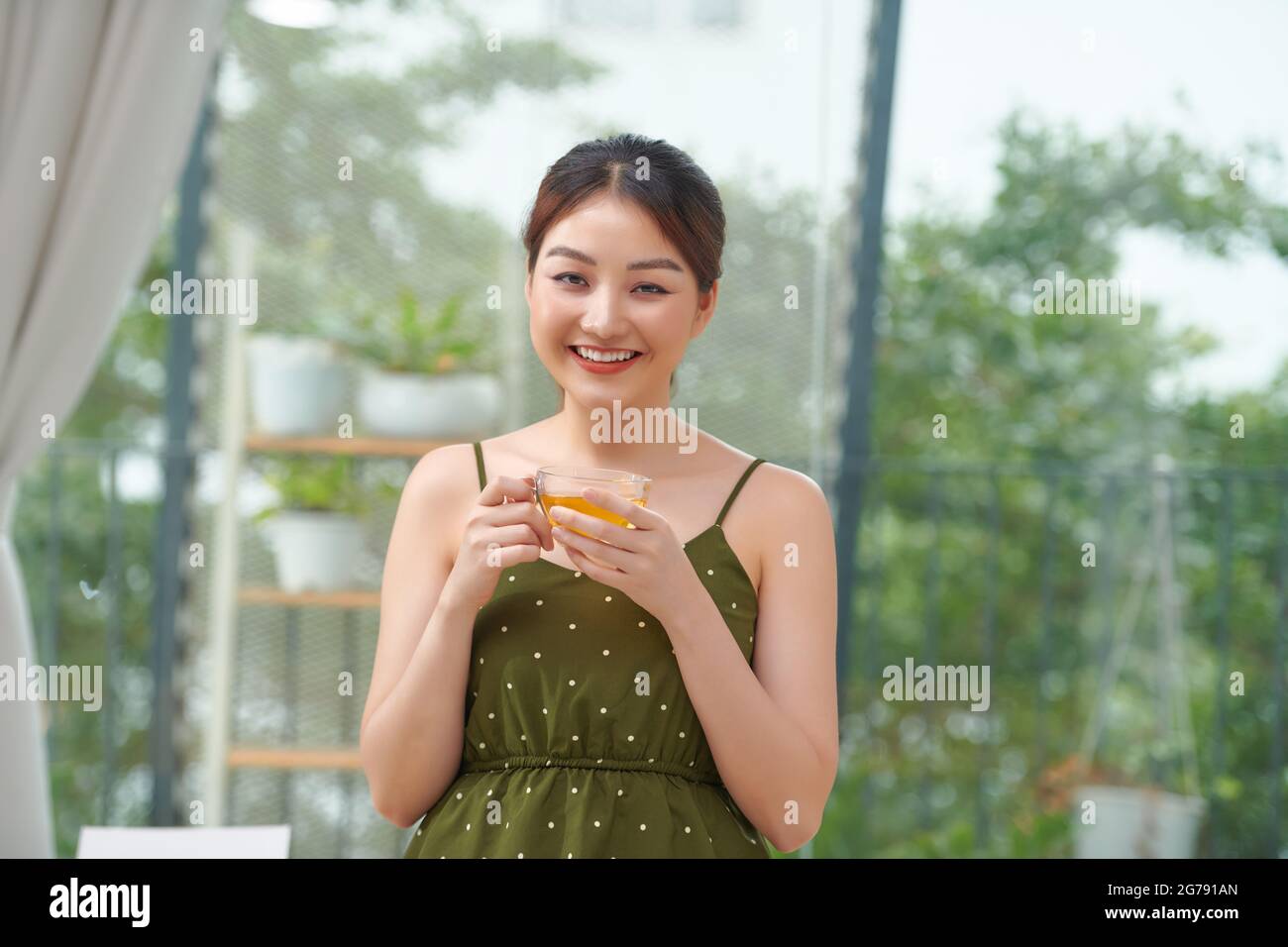Pretty young woman enjoying first morning tea near window Stock Photo ...