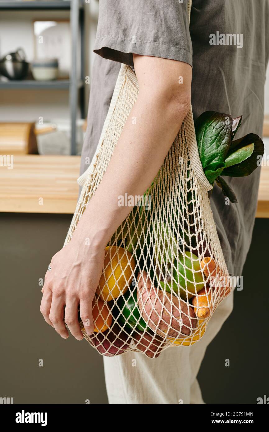 Young woman carrying bag full of fresh fruits and vegetables on ...