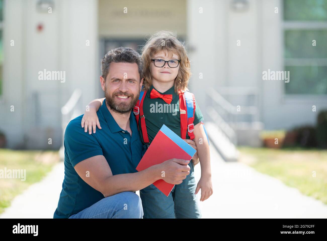 parent hug little child boy at first grade. nerd with teacher with book ...