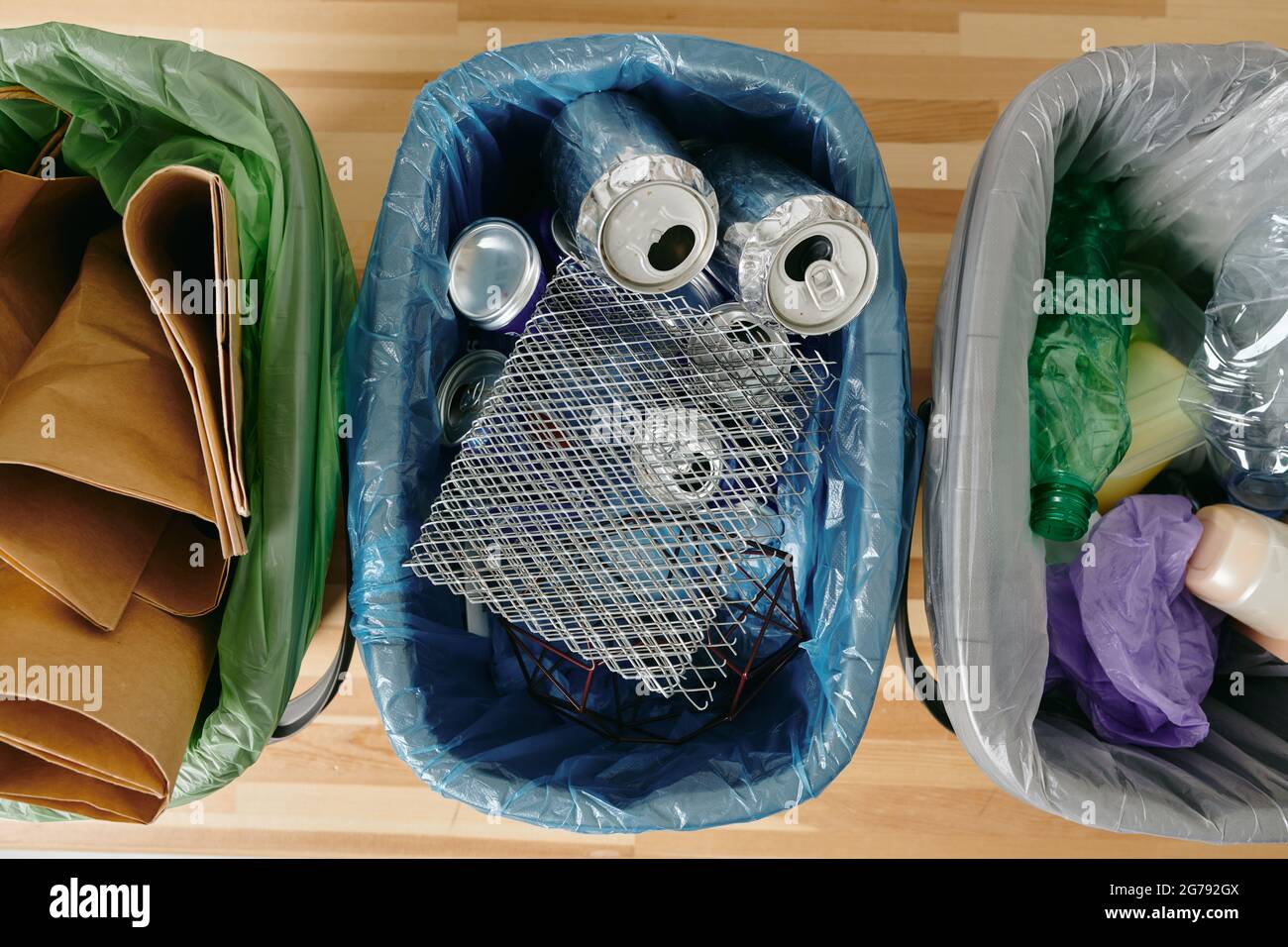 Row of three trash bins with various kinds of garbage on wooden ...